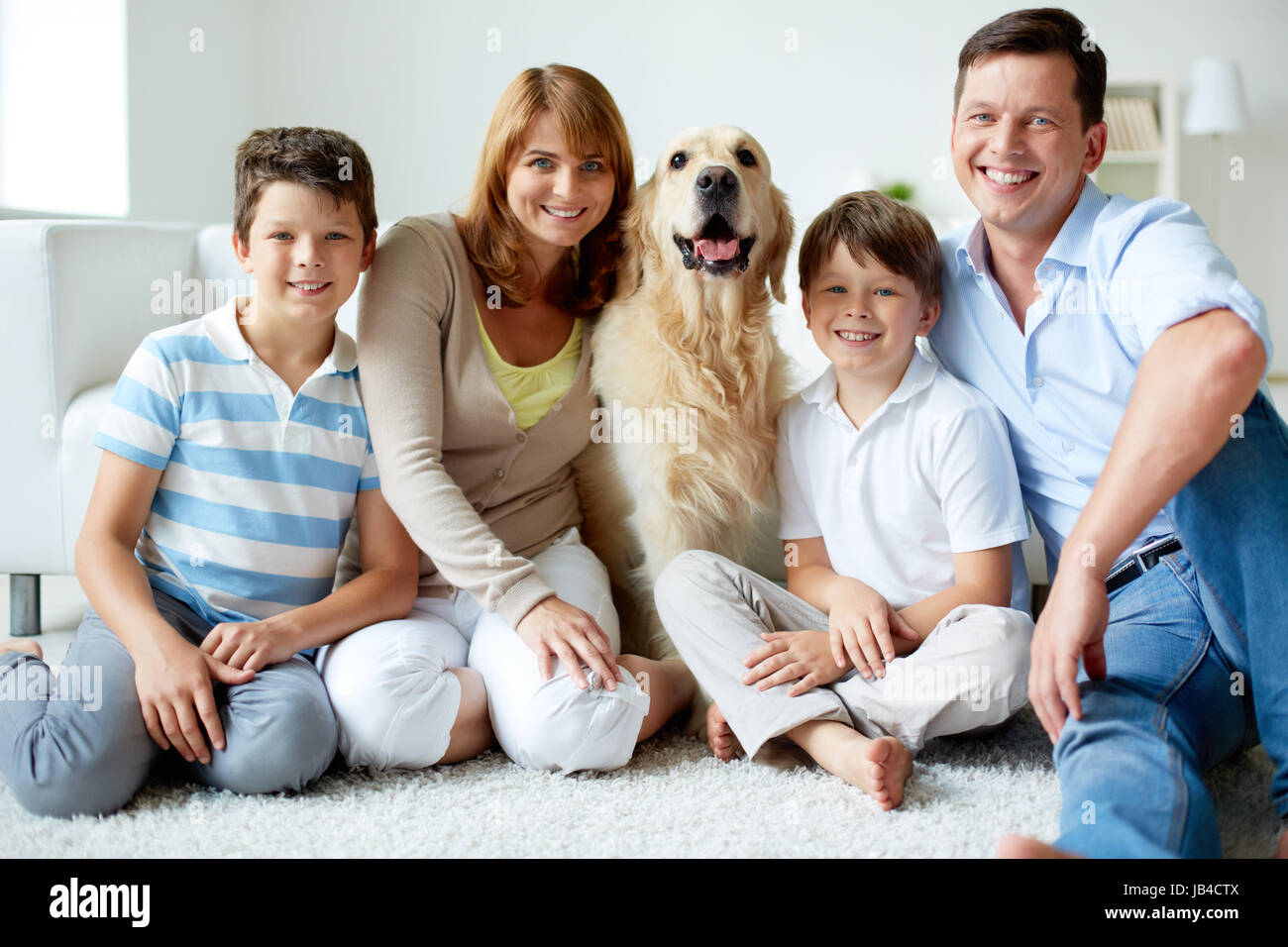 Portrait of happy family with fluffy Labrador having rest at home Stock ...