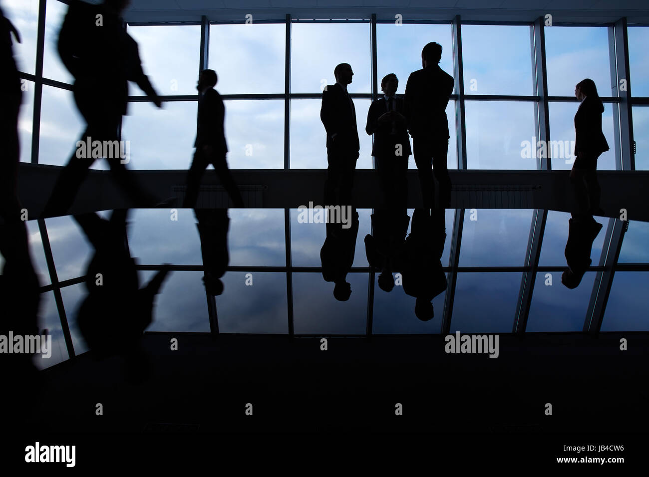Three white collar workers communicating in office against window with ...
