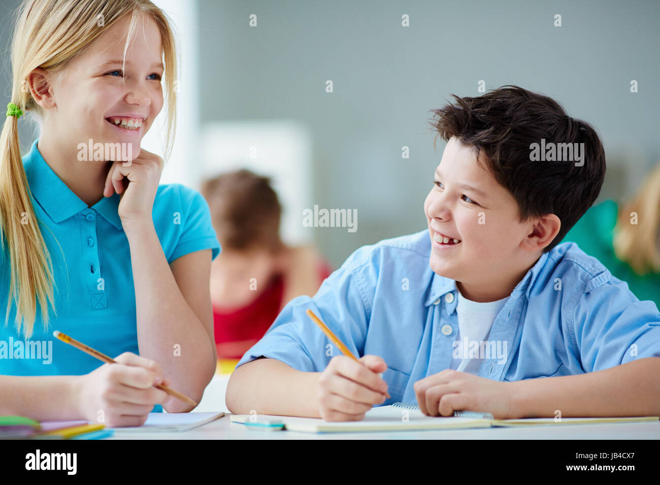Portrait of two diligent pupils laughing while drawing at lesson Stock ...