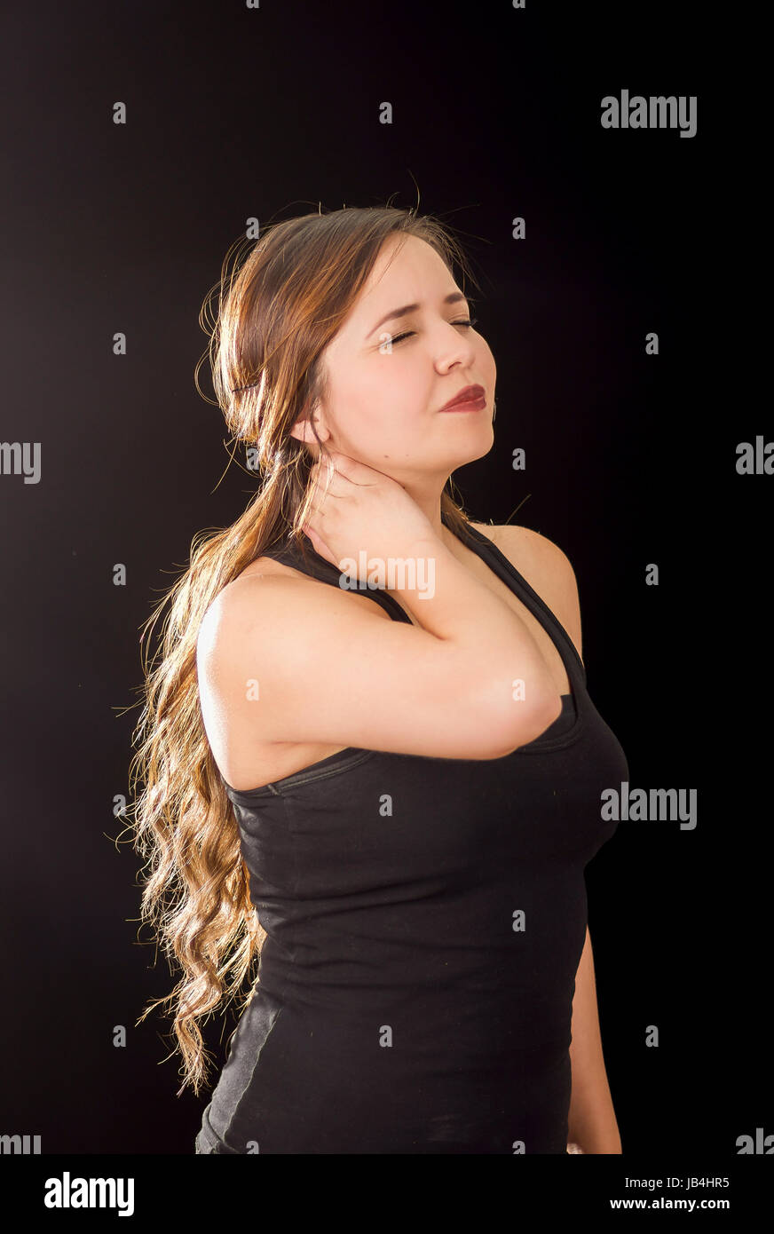 Beautiful young lady Suffer crick after workout in a black background ...
