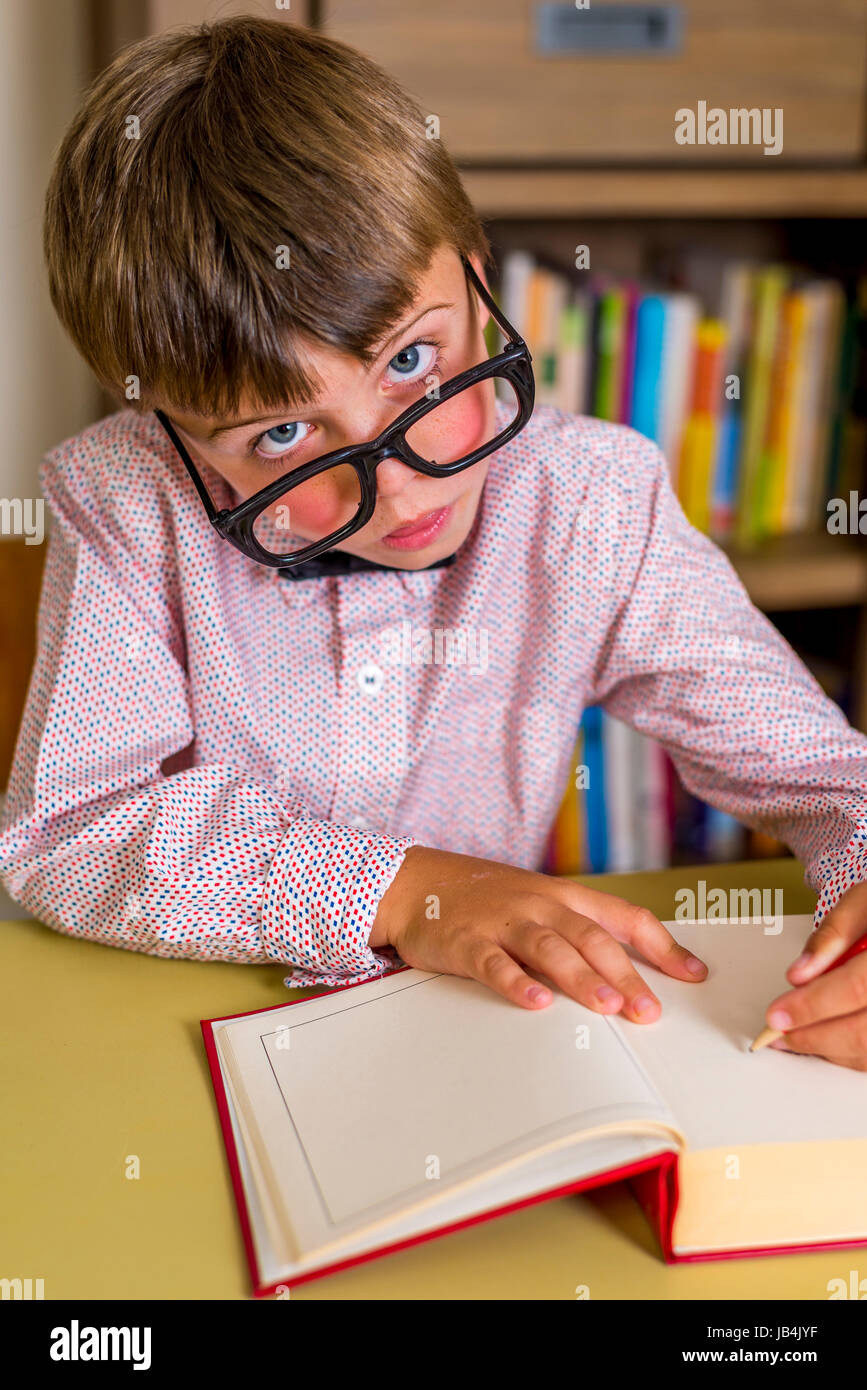 little nerdy boy with geeky goggles, writting in a book Stock Photo - Alamy