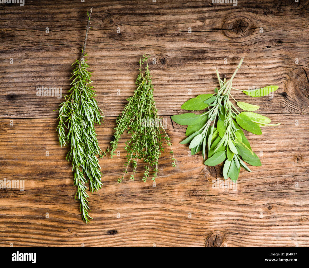 Rosemary, thyme and sage herbs on a wooden table Stock Photo - Alamy