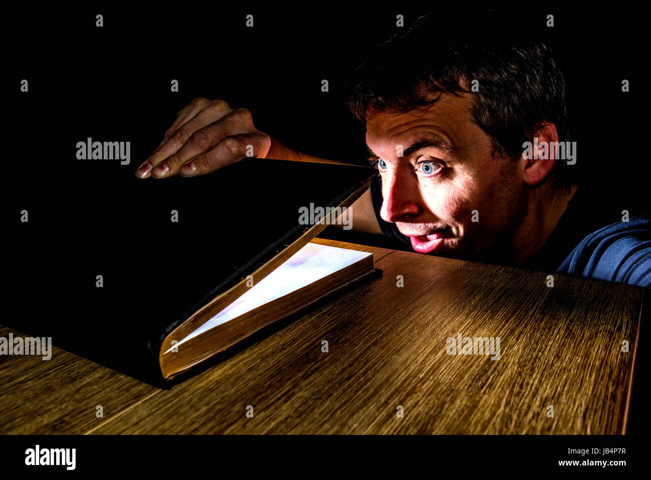 man looking surprised at a light inside a book Stock Photo - Alamy