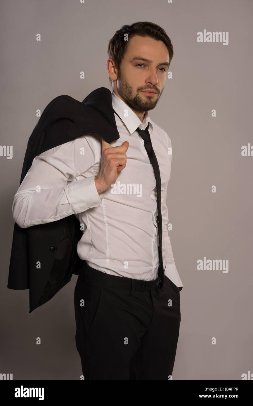 Handsome young businessman with his jacket thrown over his shoulder ...