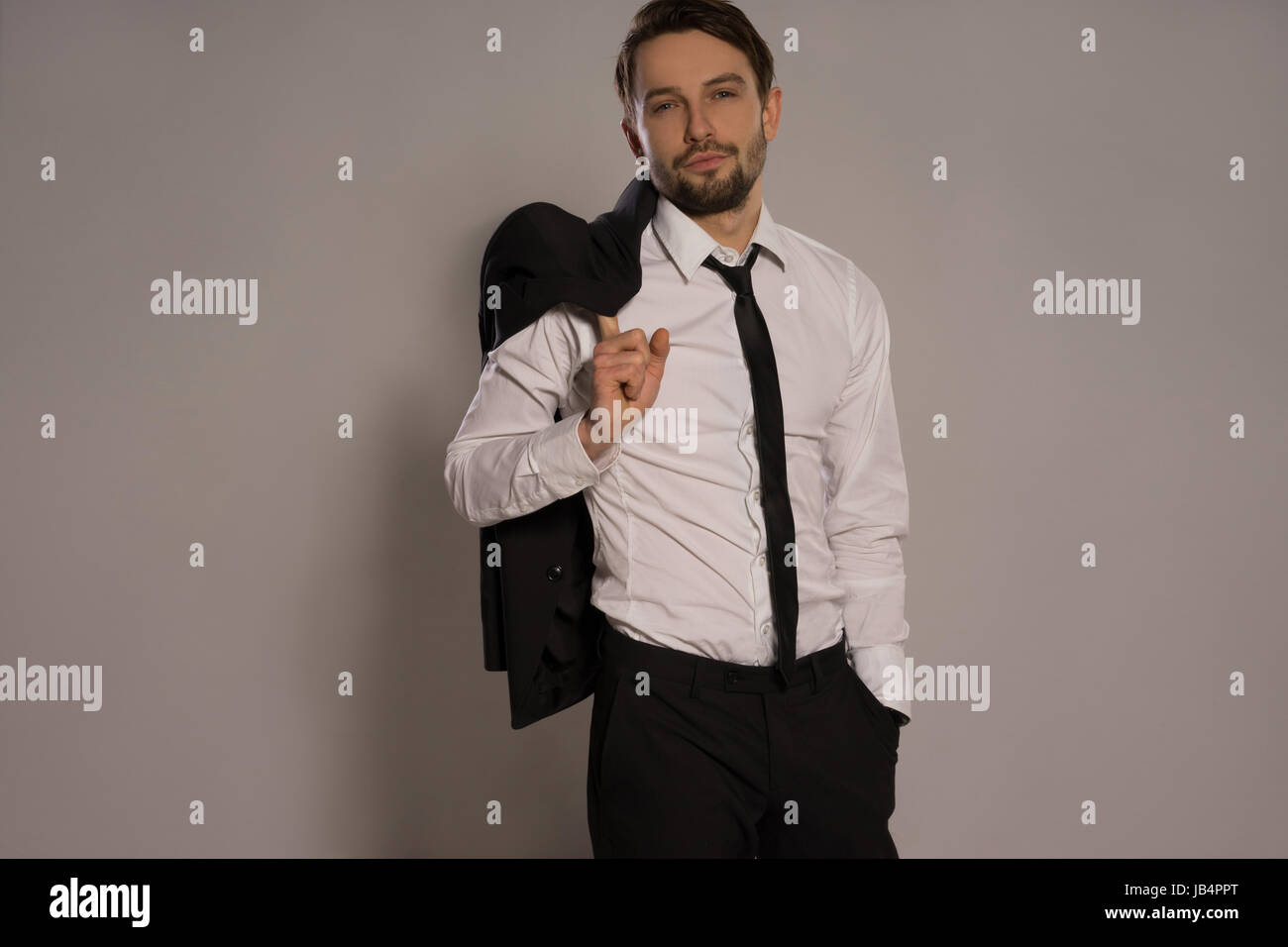 Handsome young businessman with his jacket thrown over his shoulder ...