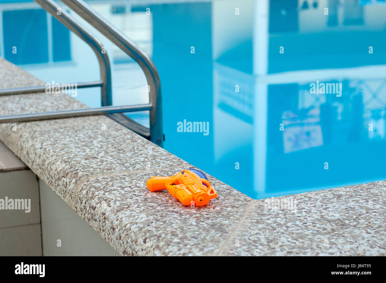 Colorful water pistol along edge of a swimming pool Stock Photo - Alamy