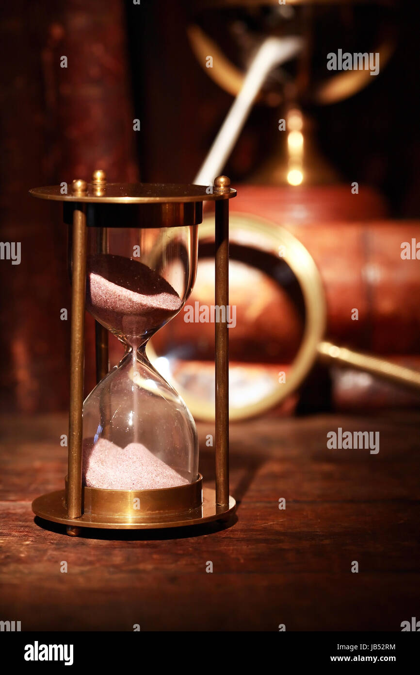 Vintage still life. Hourglass near old books against dark background ...