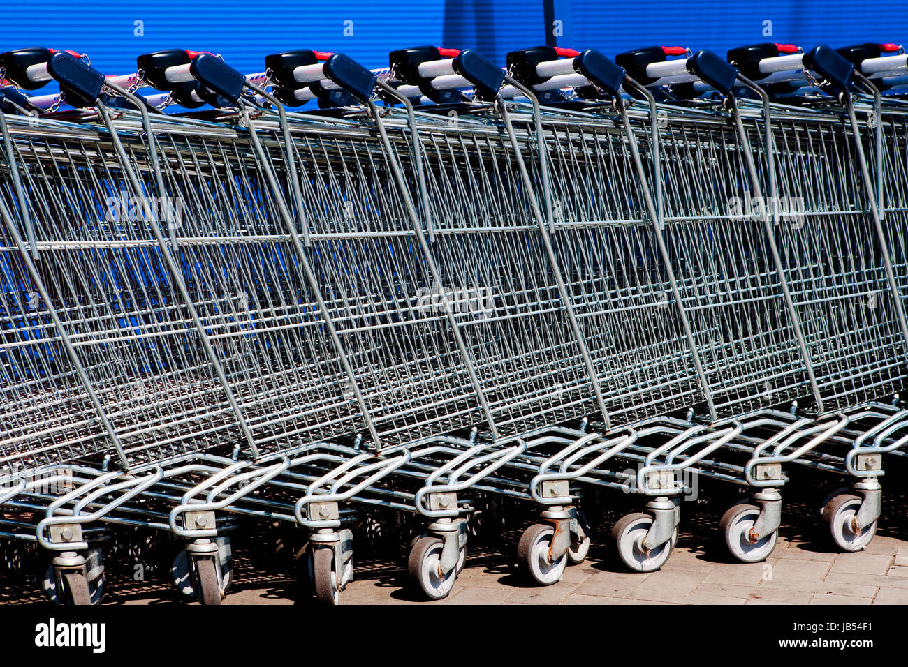 a line of empty supermarket shopping carts against blue wall Stock ...