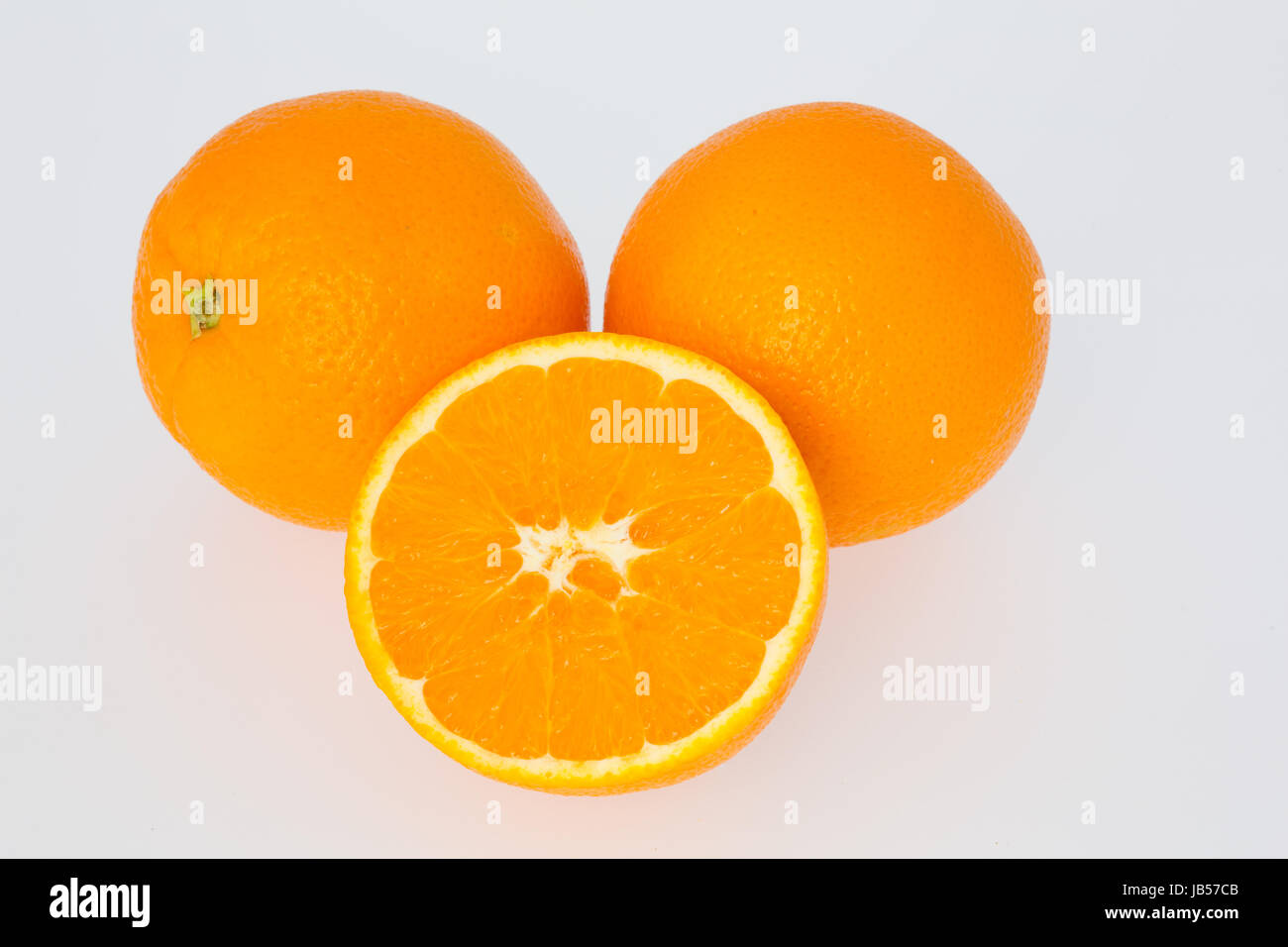 A half cut orange fruit leaning against two whole oranges Stock Photo ...