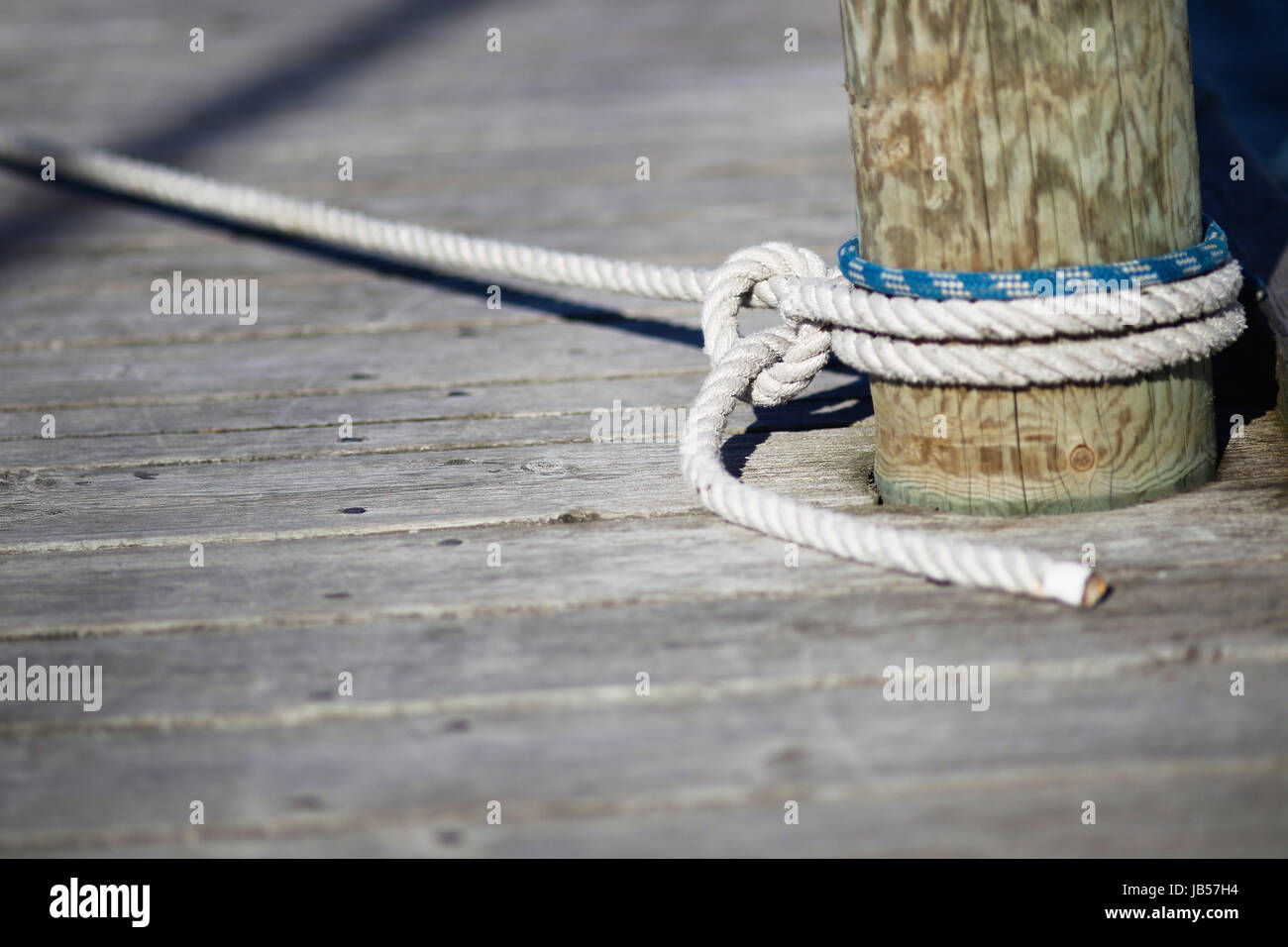 Mooring rope tied around pole on marina pier Stock Photo - Alamy