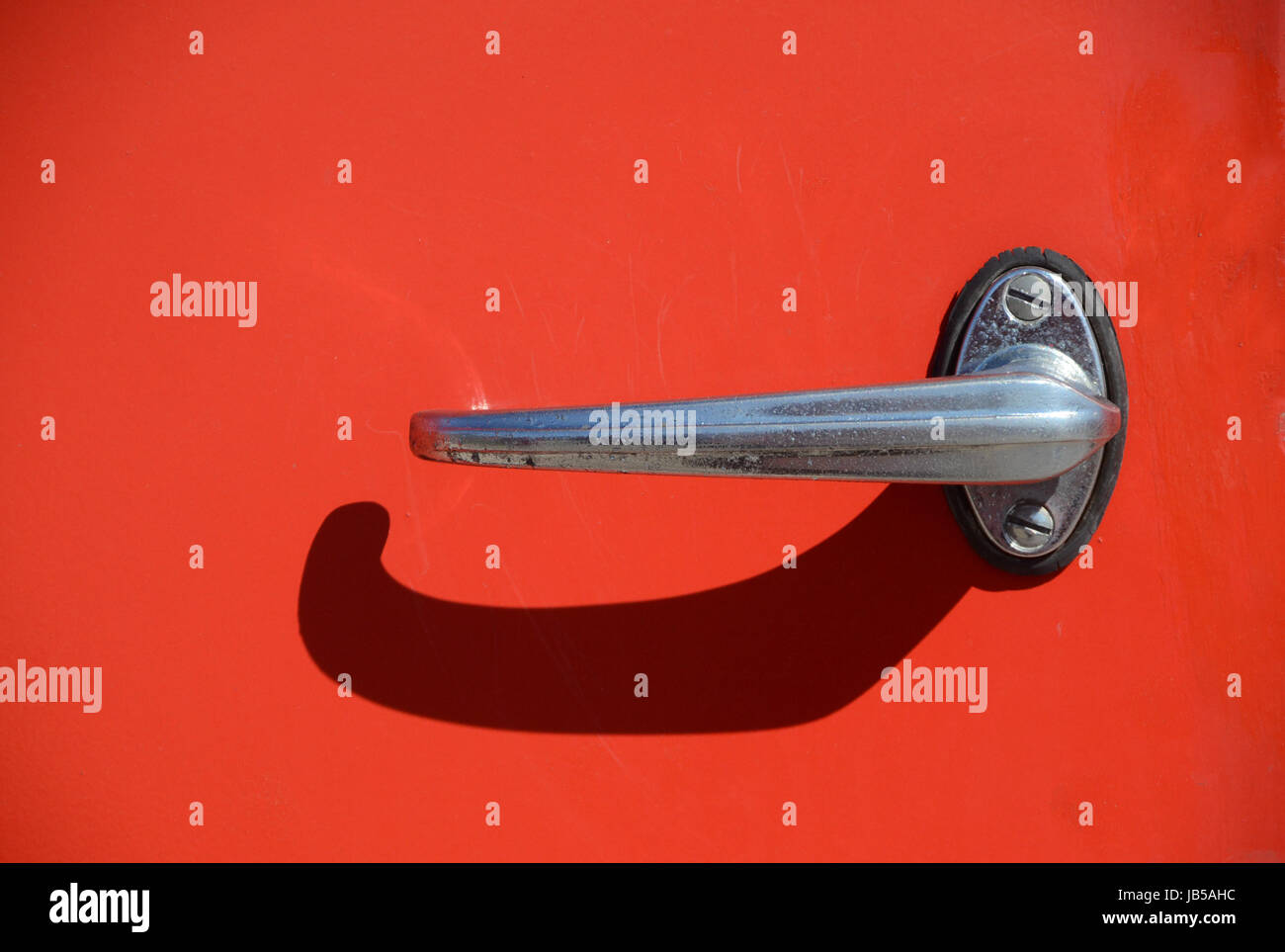 Crome handle with shadow on a red background Stock Photo - Alamy