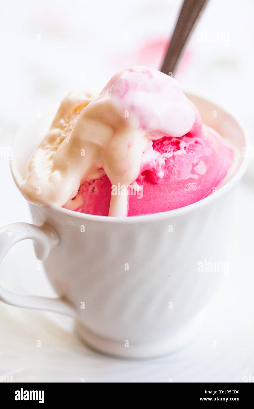 Closeup of cup with raspberry and vanilla ice cream and spoon on light ...
