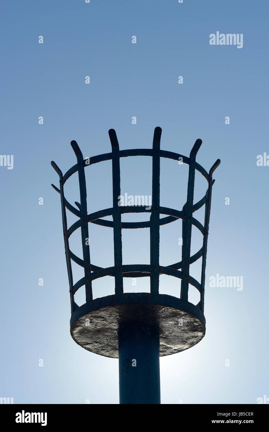 Empty beacon brazier in silhouette against blue sky on seafront ...