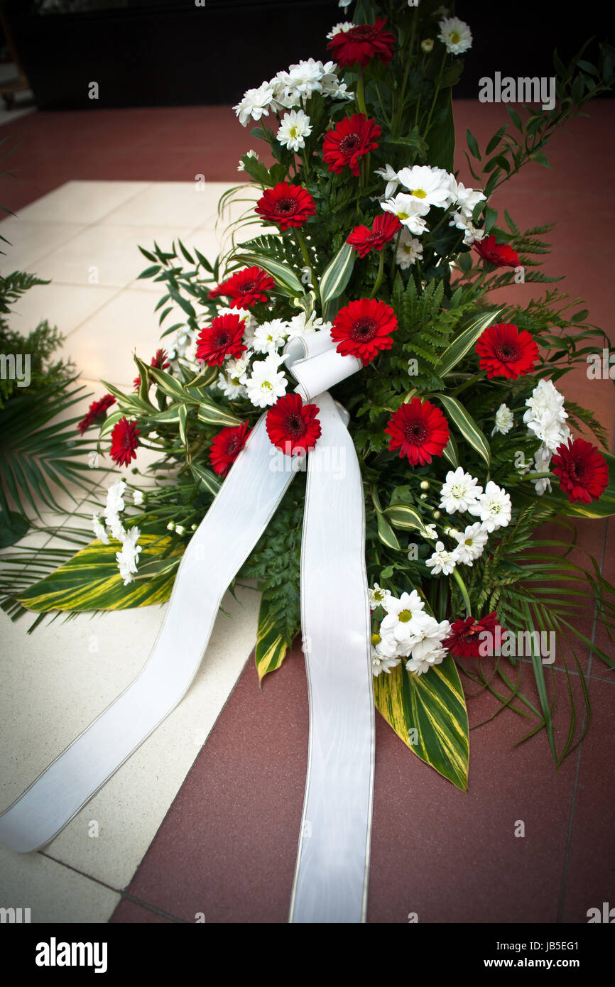 Large funeral flowers in wreath with ribbon on floor Stock Photo - Alamy