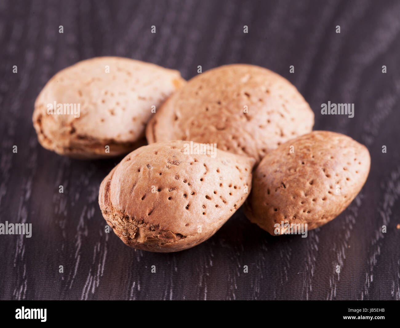 Four almonds over a dark wooden table Stock Photo - Alamy