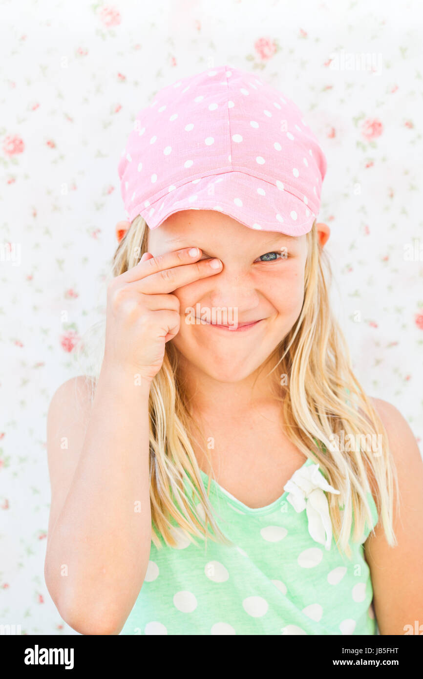 Portrait of cute smiling young girl looking through one eye while ...
