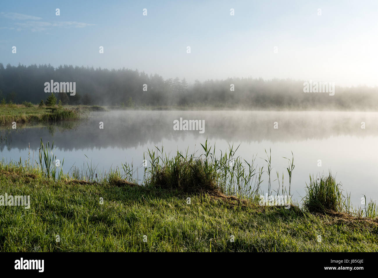 reflections in the lake water at sunrise with morning mist over the ...