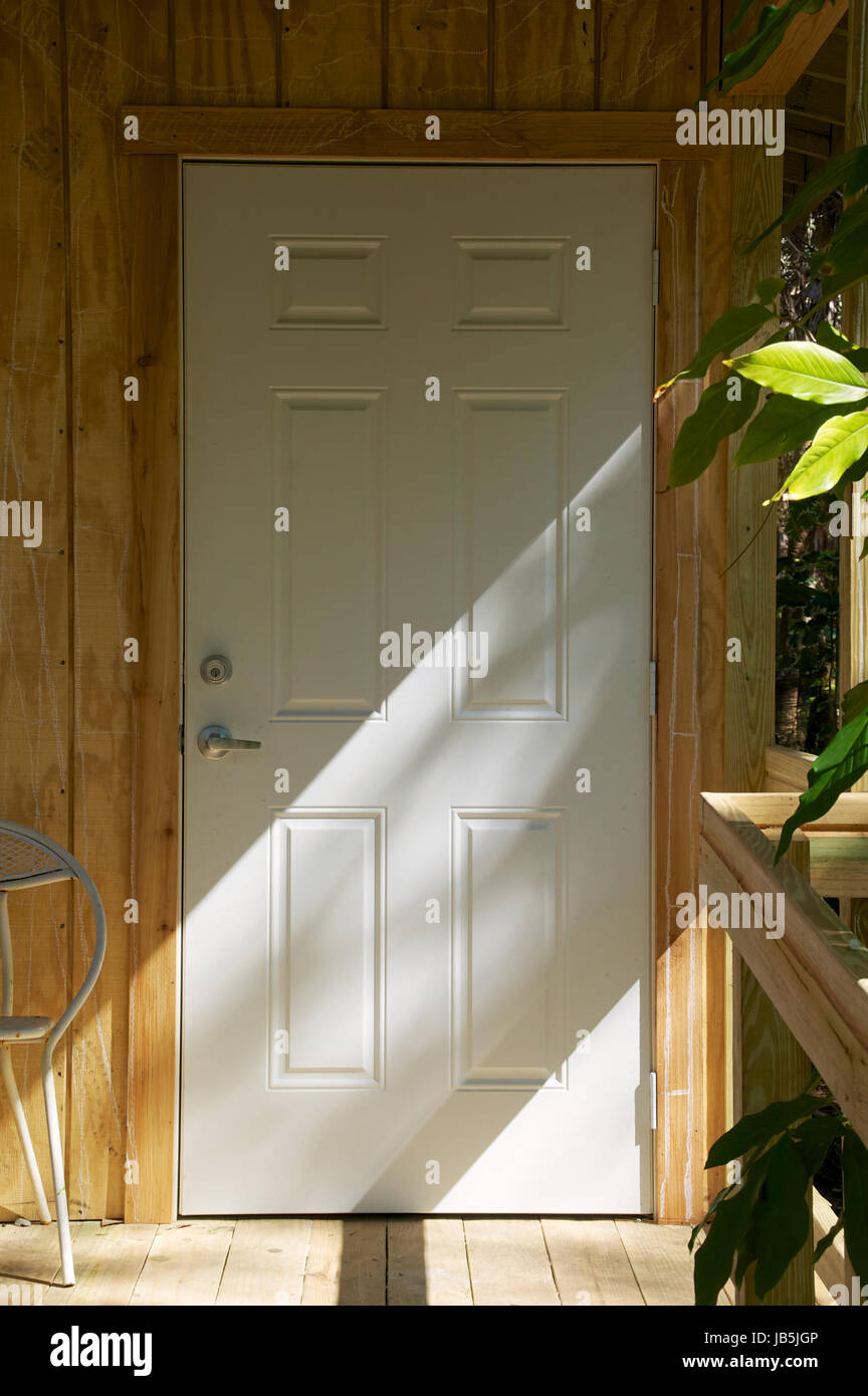 A closed door on exterior of newly constructed building, half in shade ...