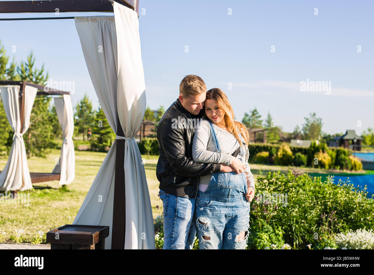 Happy and young pregnant couple hugging in nature Stock Photo - Alamy
