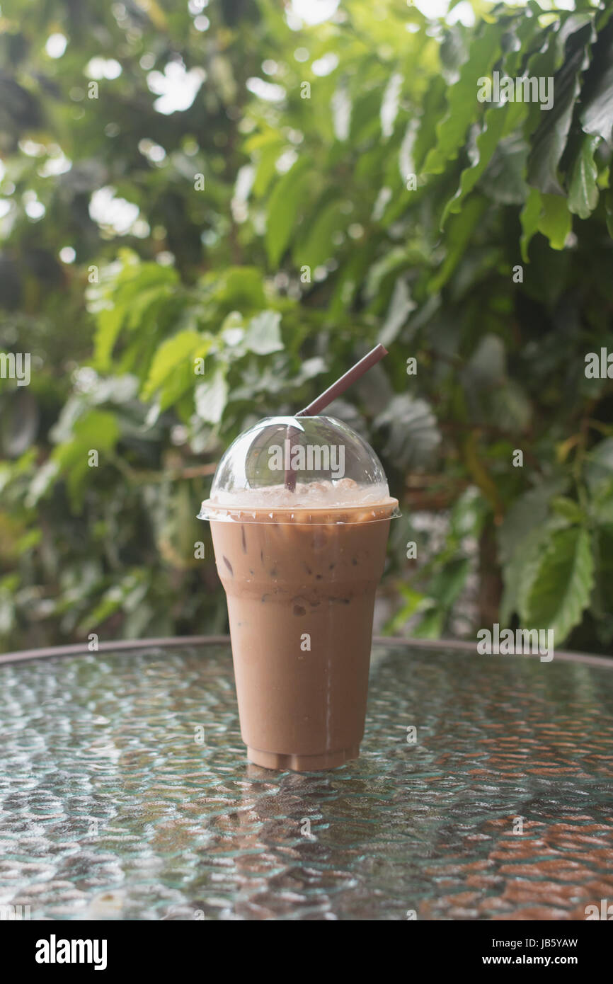 Plastic glass of Ice coffee mocha on the glass table in outdoor cafe ...