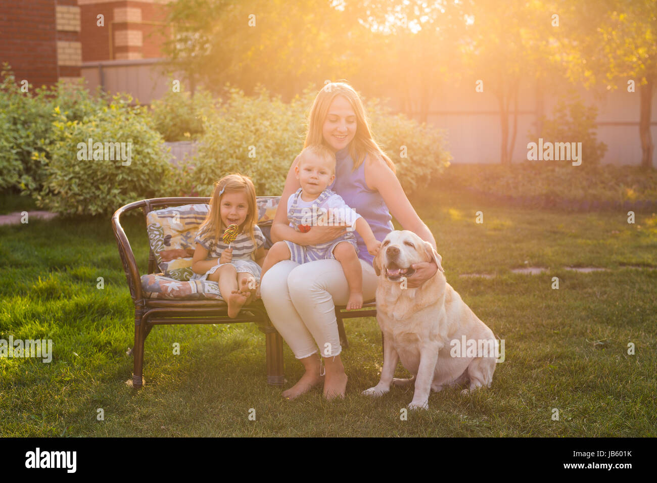 Happy mother and two children with Golden Retriever dog in the garden ...