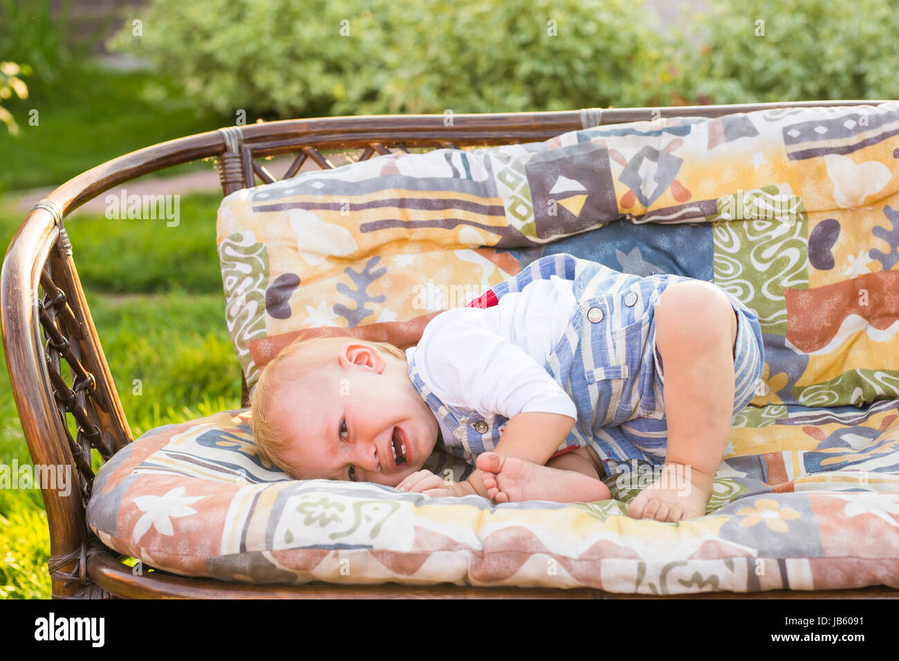 Cute unhappy baby boy with blond hair crying outdoors on sunny summer ...