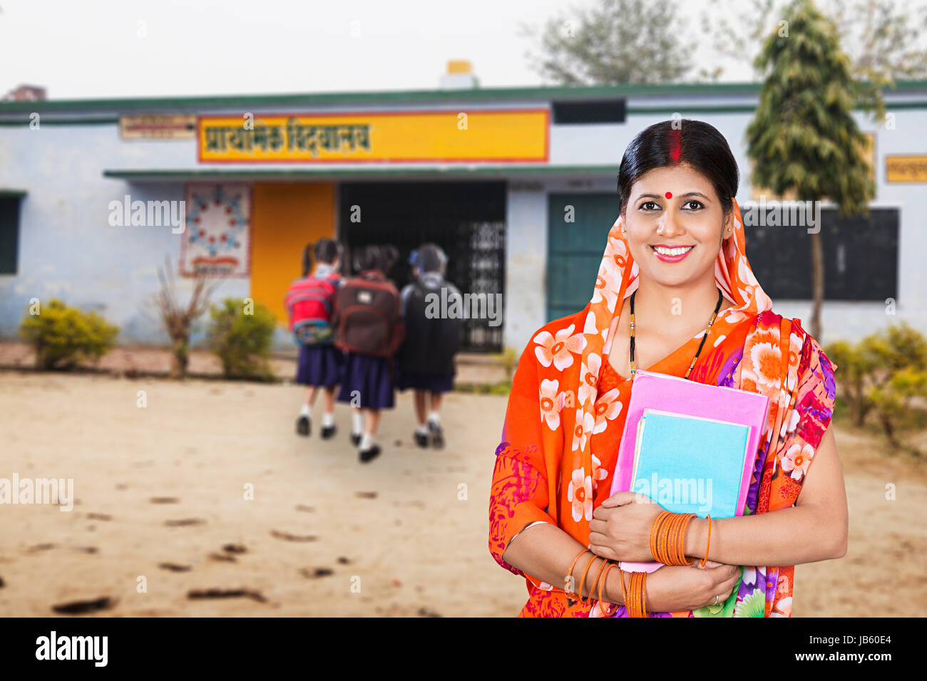 Indian Rural Woman Teacher Holding Book Standing In Village School Education Concept Stock