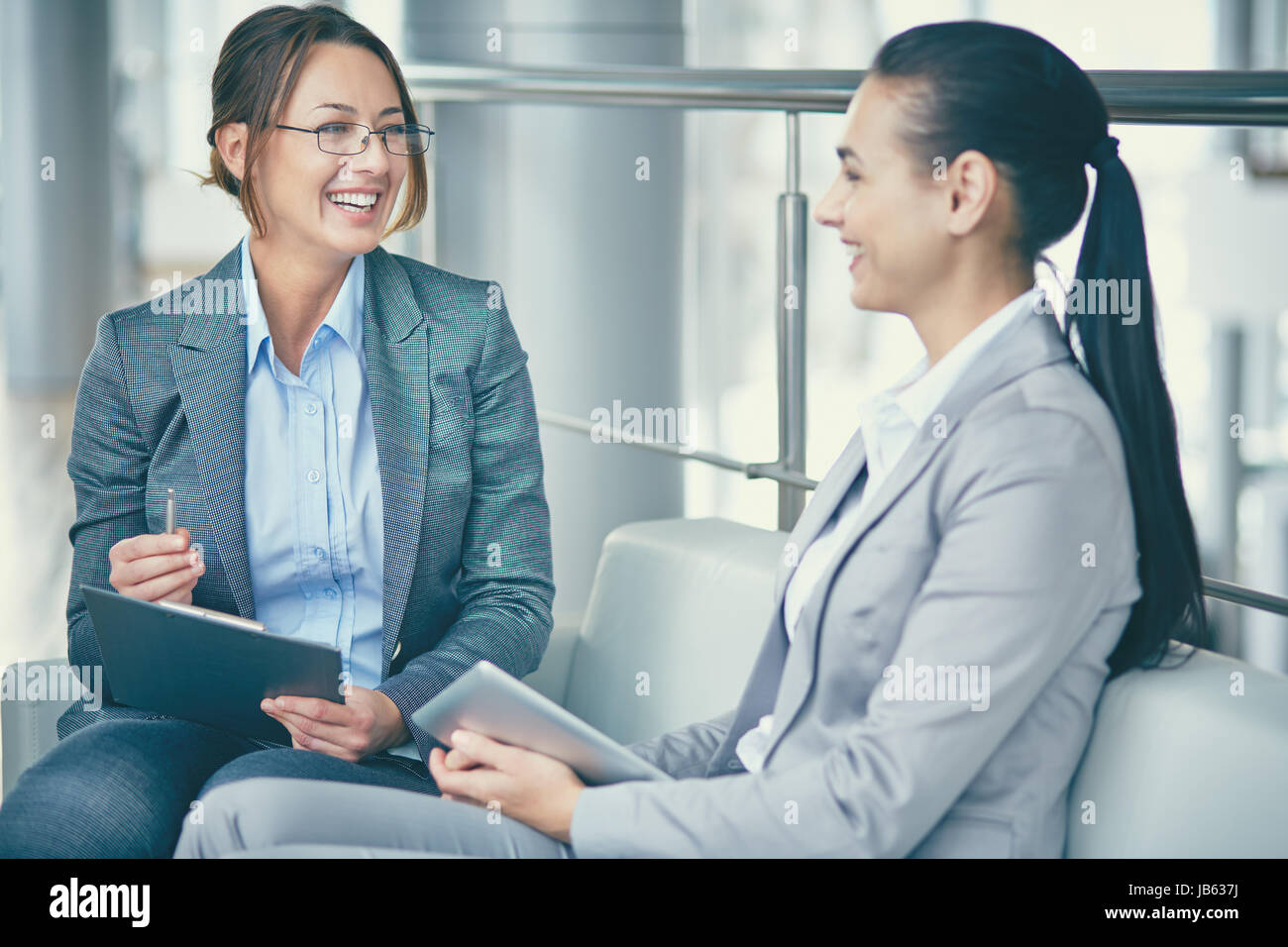 Image of two happy businesswomen sitting and talking Stock Photo - Alamy
