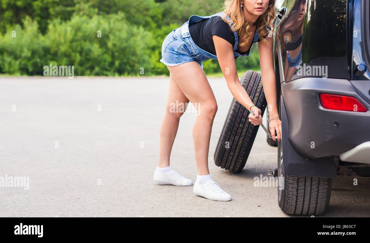 Woman changes the wheel of car on a road Stock Photo - Alamy