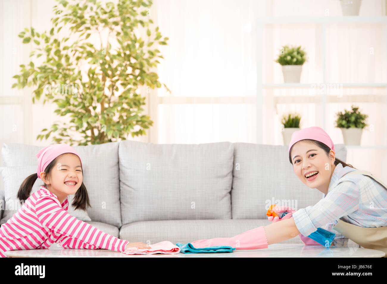 happy mother with kids spring cleaning room and having fun playing at home. A young woman and a ...