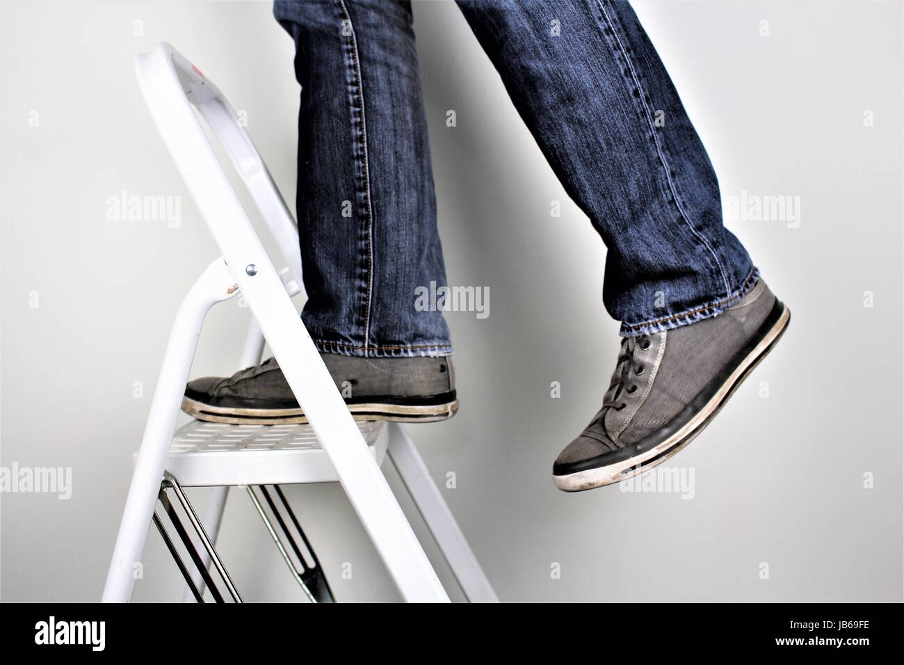 Anonymous man reaching on top of ladder climbing, indoors studio people ...