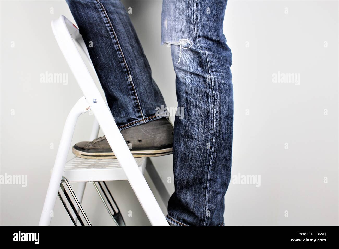 Anonymous man reaching on top of ladder climbing, indoors studio people ...