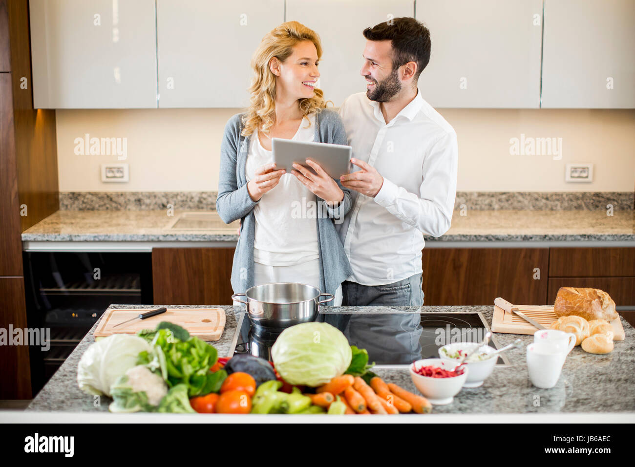 View at young man helping his girlfriend cooking in modern kitchen ...