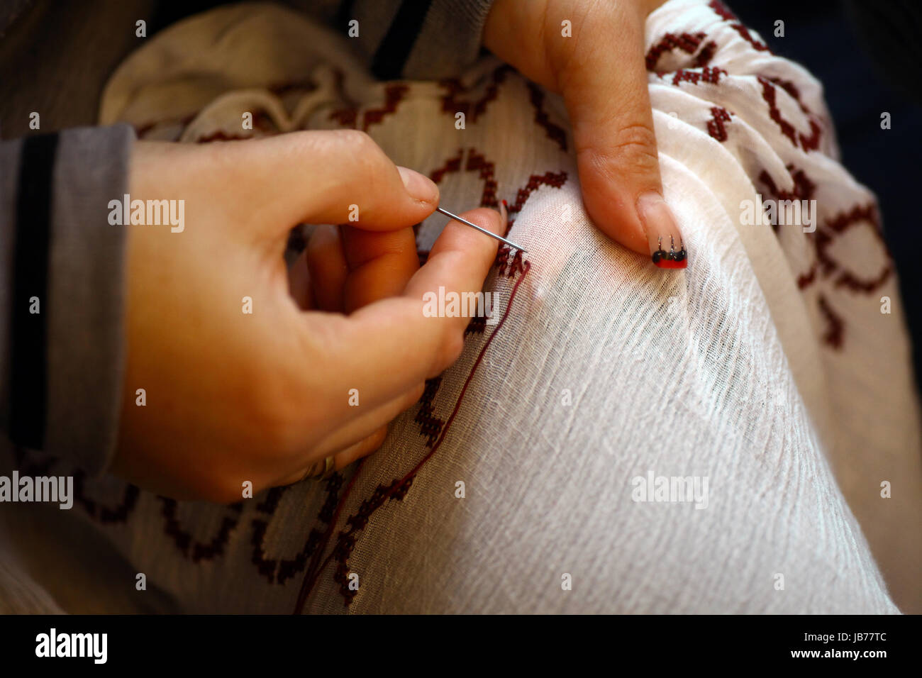 Color shot of two hands holding a needle and sewing Stock Photo - Alamy