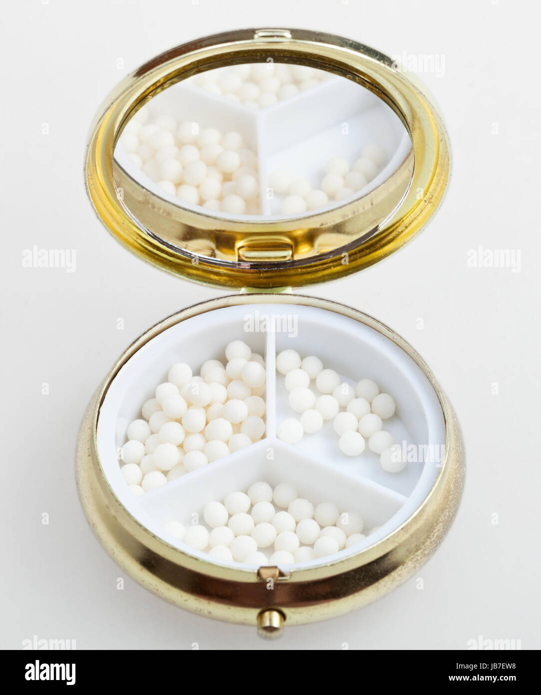 compact pill box with sugar homeopathy balls on white background Stock ...