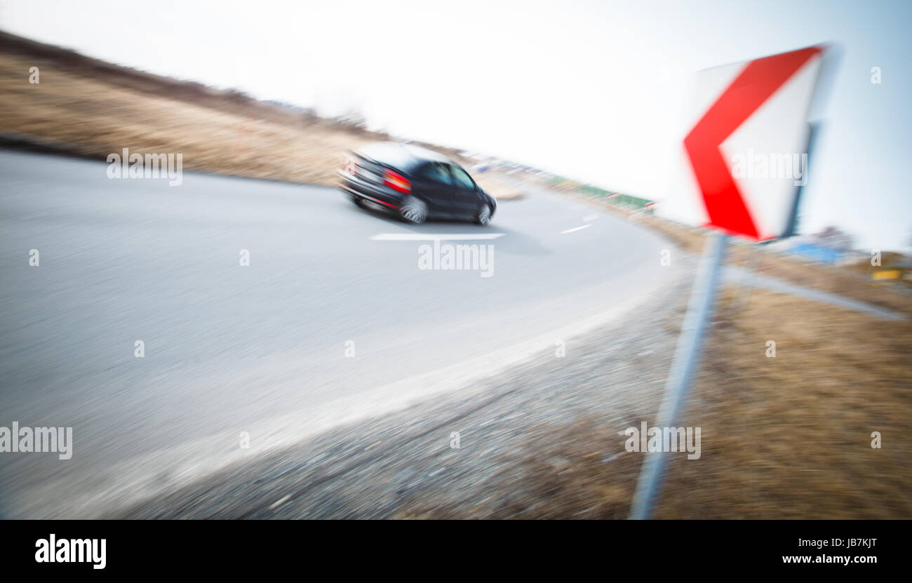 Traffic concept: car driving fast through a sharp turn (motion blur is ...