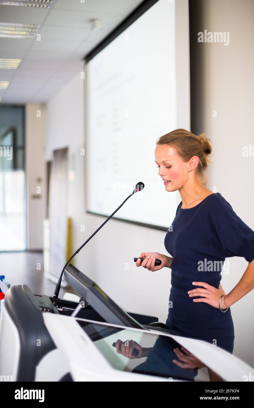 Pretty, young business woman giving a presentation in a conference ...