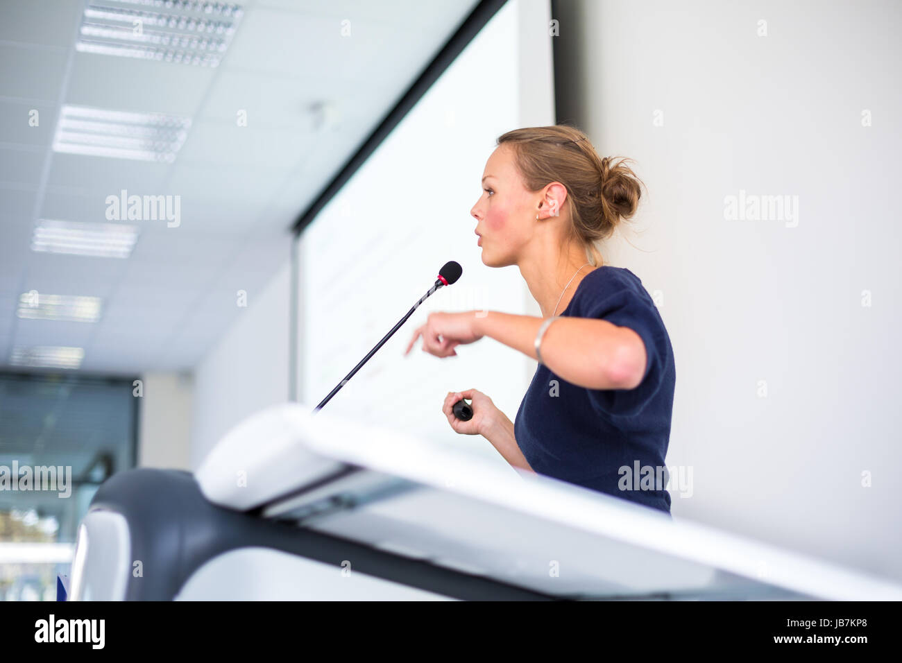 Pretty, young business woman giving a presentation in a conference ...