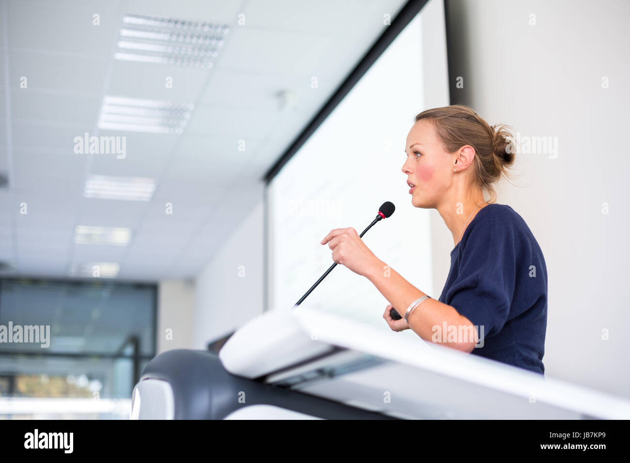 Pretty, young business woman giving a presentation in a conference ...