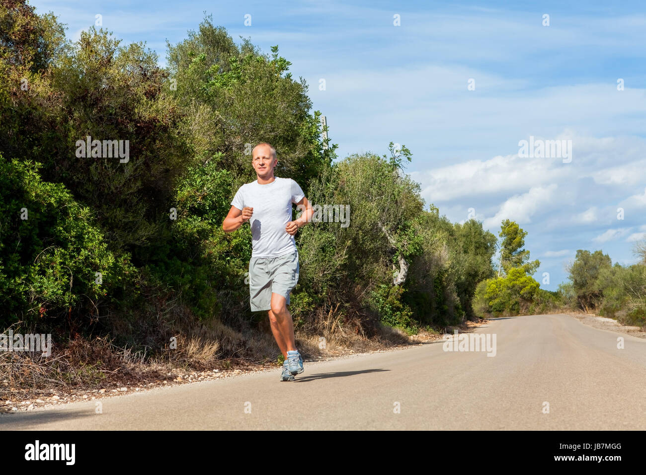 Junger sportlicher mann beim rennen joggen im sommer im freien auf ...