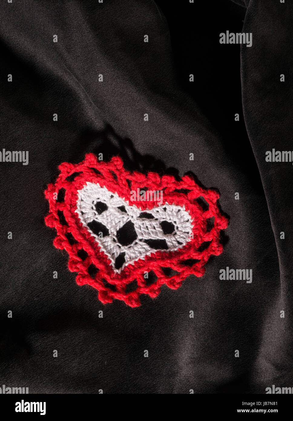 Heart shape made of red textile on black satin Stock Photo - Alamy