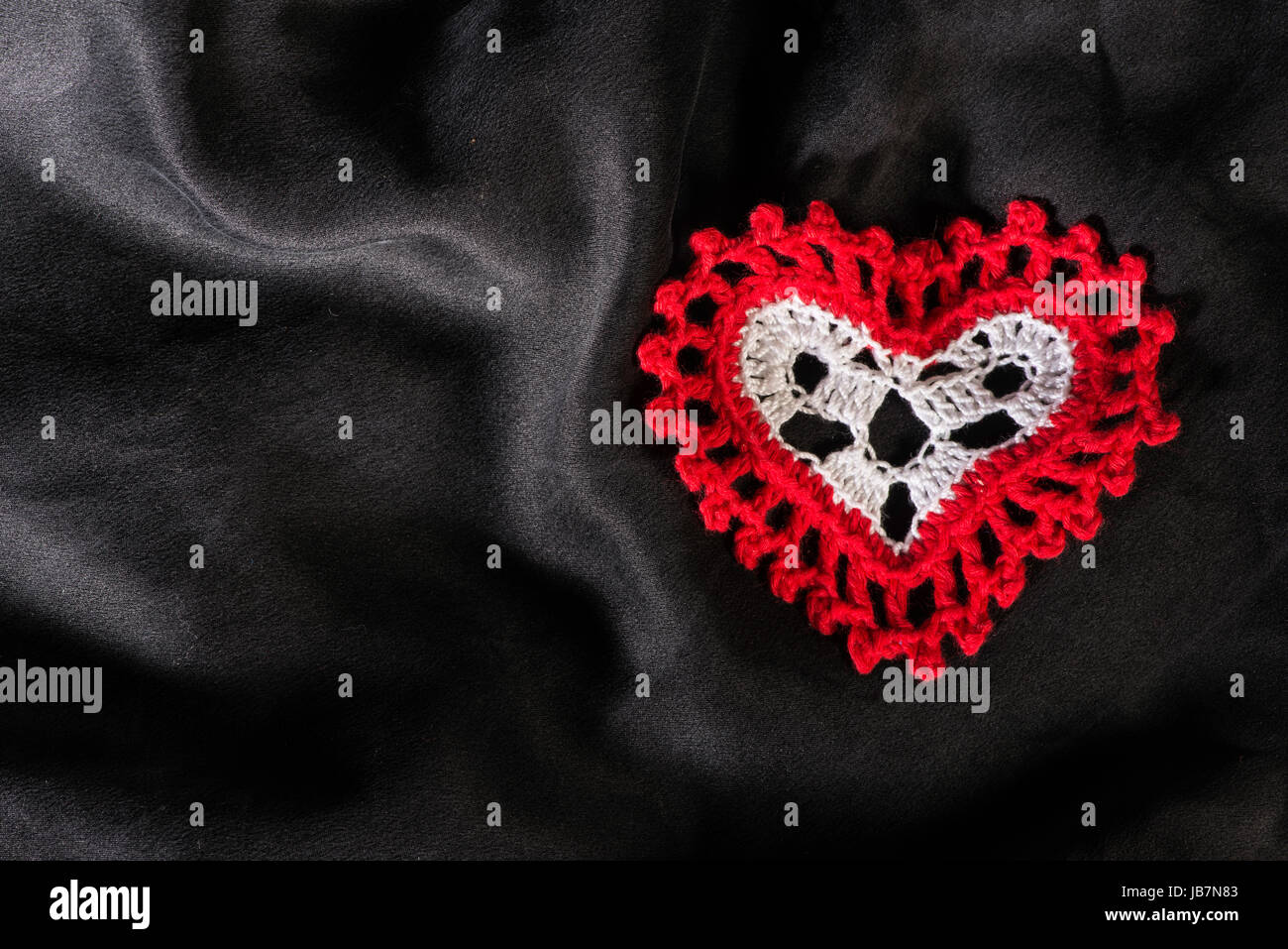 Heart shape made of red textile on black satin Stock Photo - Alamy