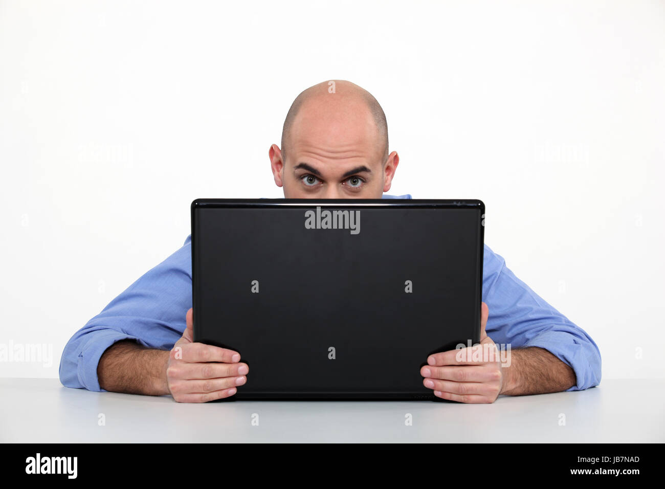 Man hiding behind laptop Stock Photo - Alamy