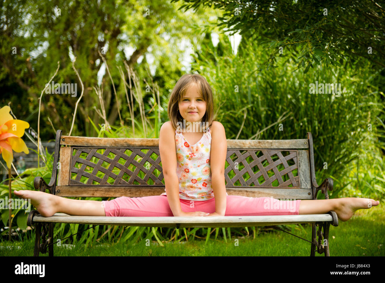 Child (little girl) performing gymnastic pose on bench outdoor in ...