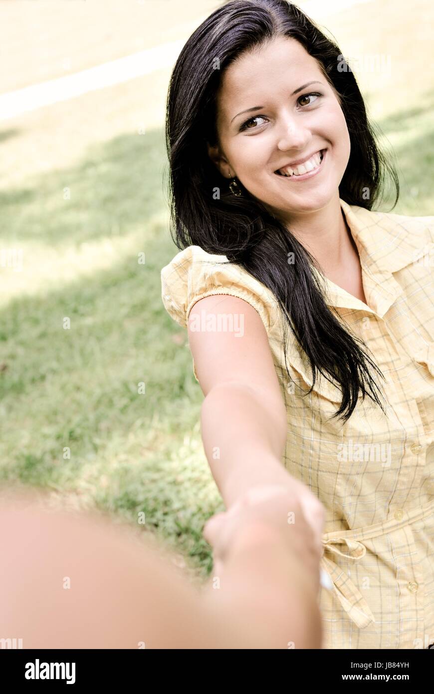Young smiling woman stretching her hand and receiveing help Stock Photo ...