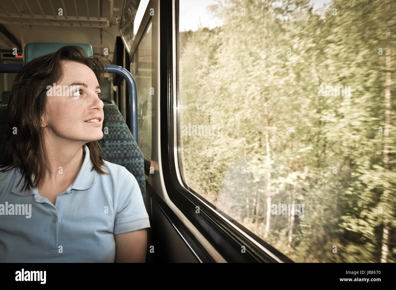 Young woman passanger sitting inside train and looking trough window ...
