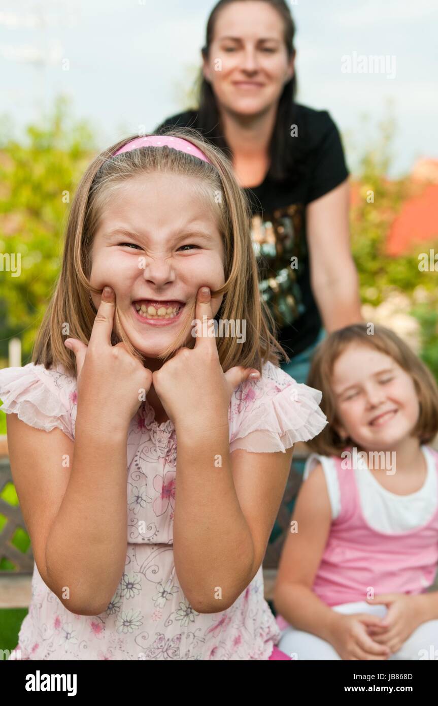 Child with cheeke expression - mother and sister in background Stock ...