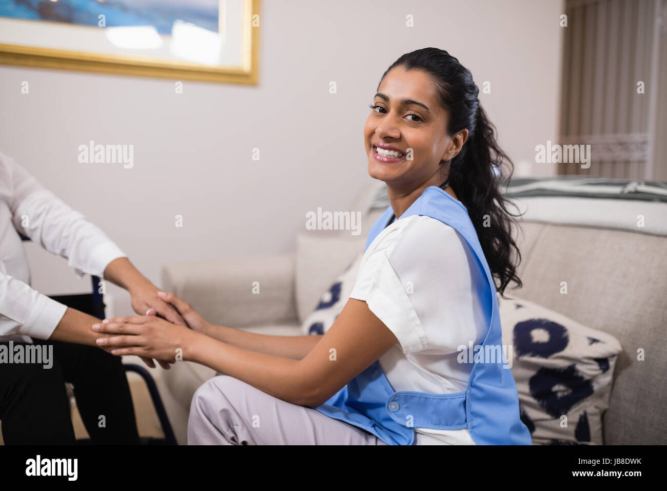 Portrait of smiling young doctor touching patient hands at home Stock ...