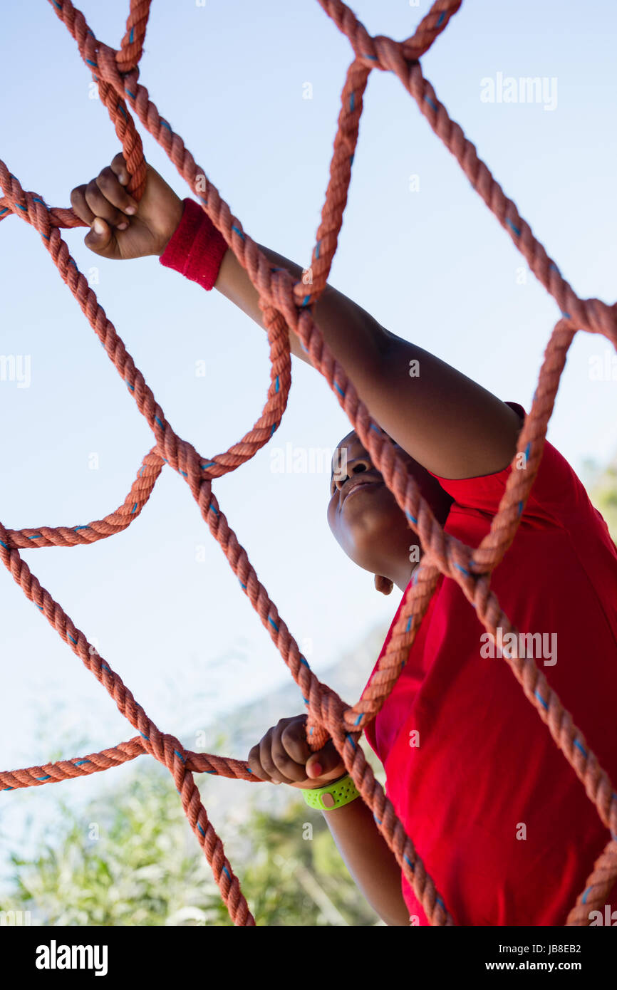 Boy climbing a net during obstacle course training in the boot camp ...
