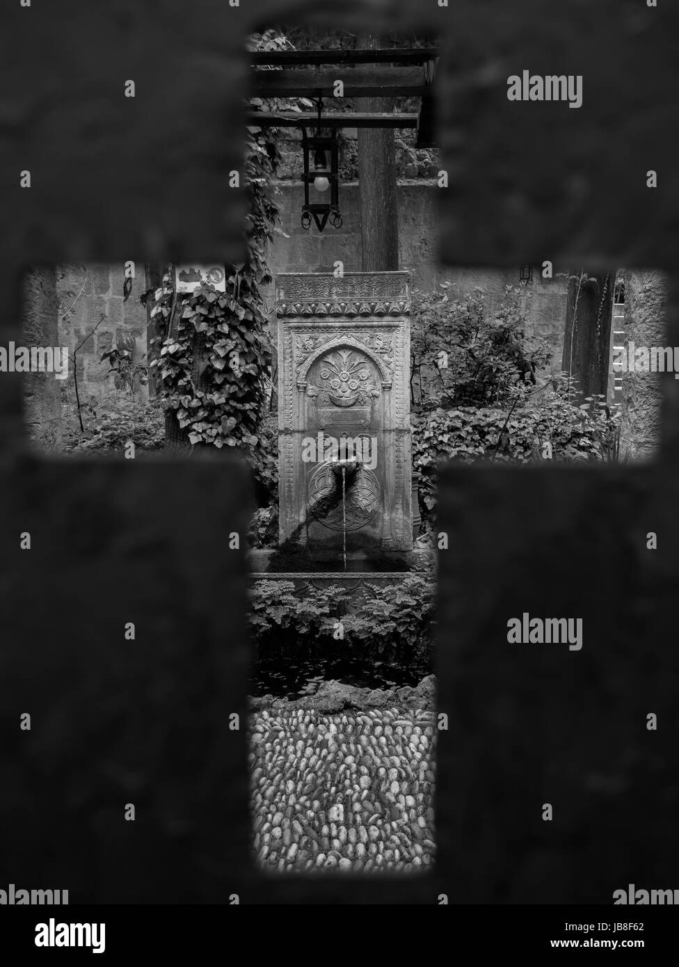 water fountain through cross shaped hole in gate Stock Photo - Alamy